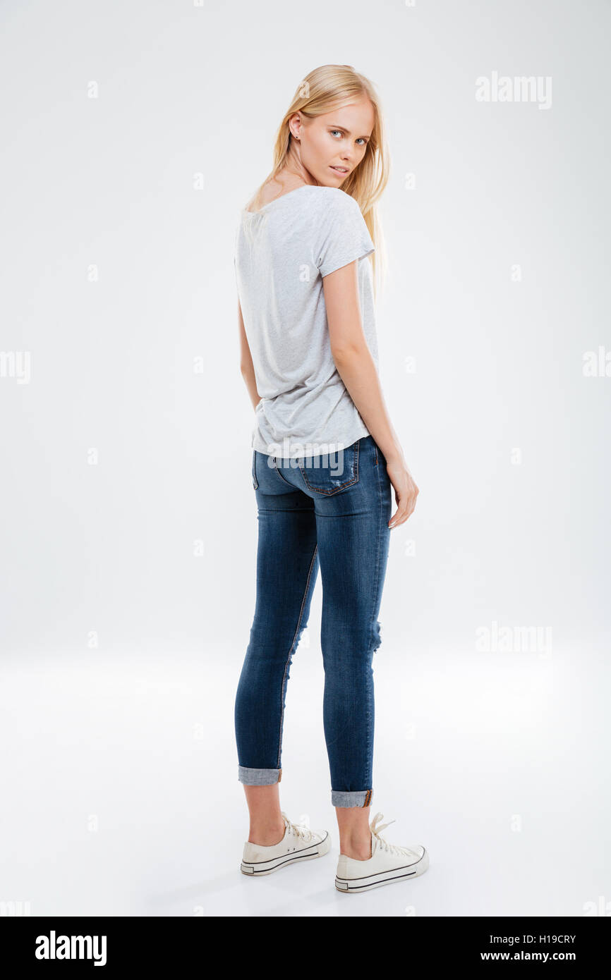 Full length portrait of a beautiful casual woman looking back at camera ...