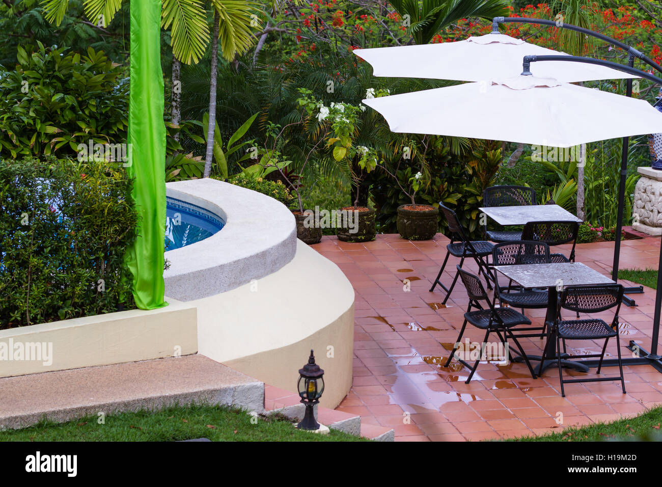 view of a lounge area with chairs under an umbrella with wet tiles ...