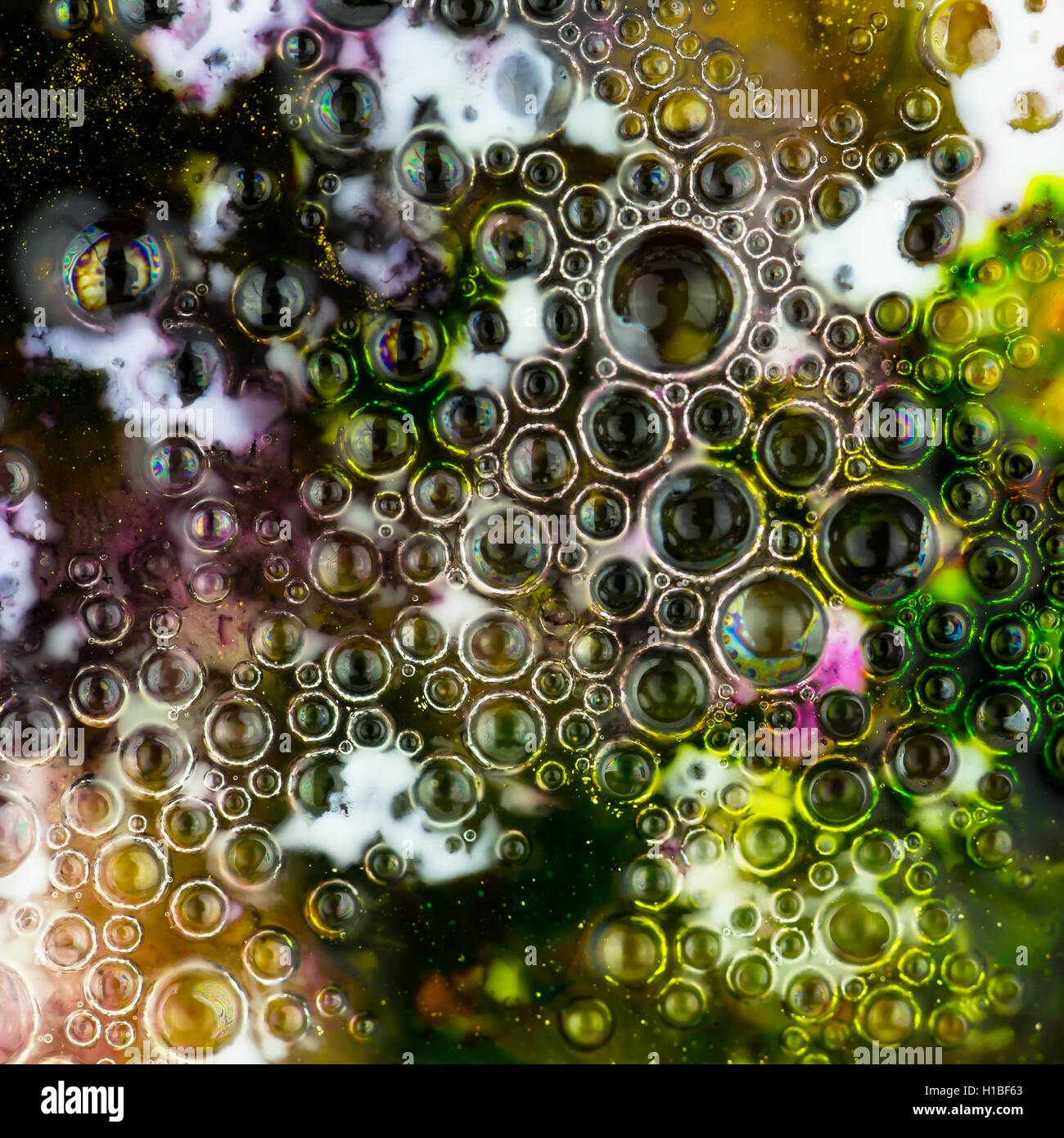 Vivid dye flowing through liquid, with bubbles rising to the surface ...