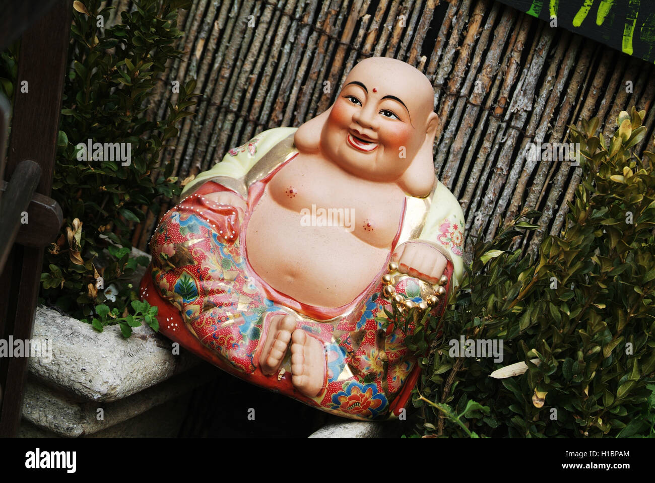 photo of a happy smiling Buddha figuring in a garden Stock Photo - Alamy