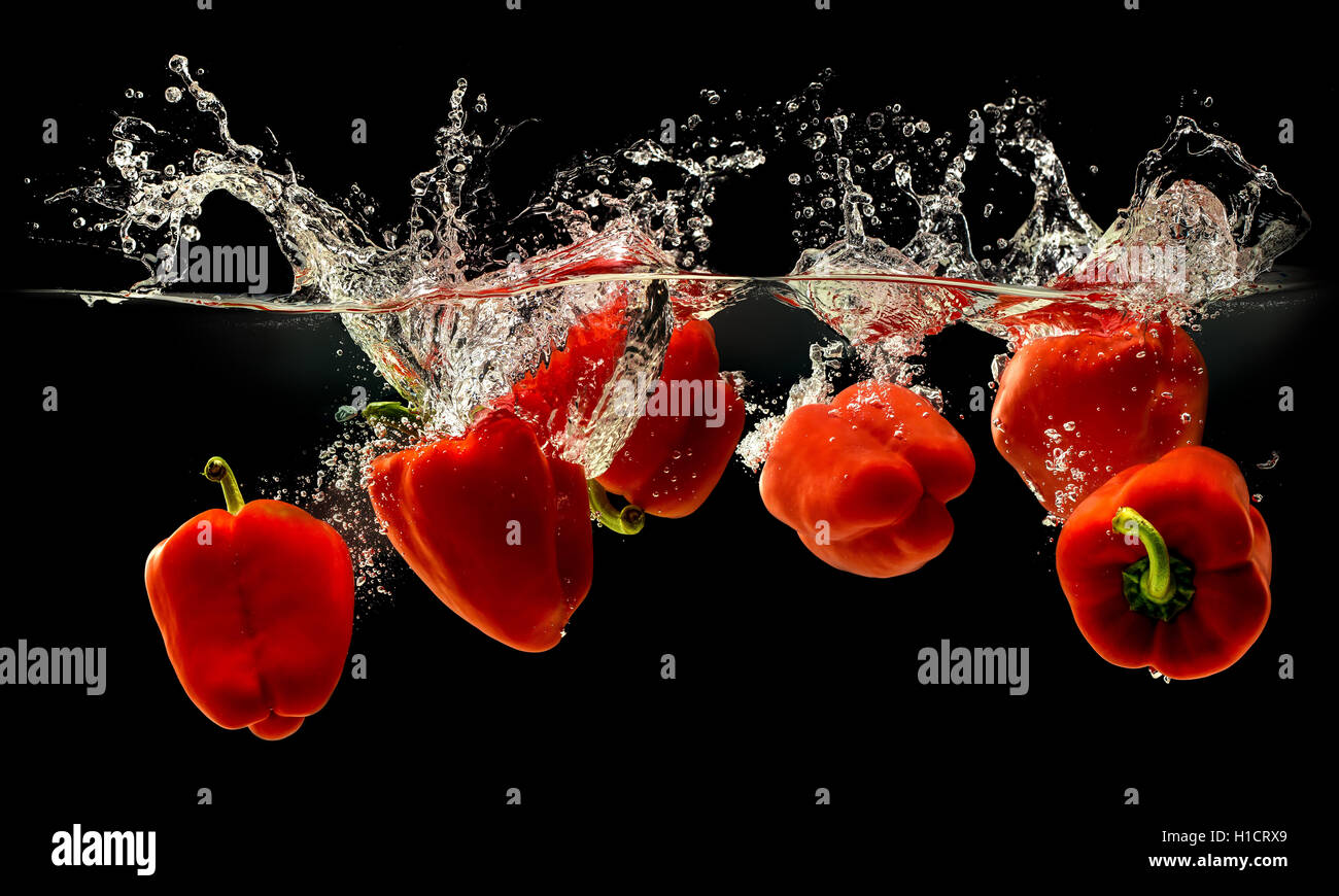 Group of bell pepper falling in water on black Stock Photo - Alamy