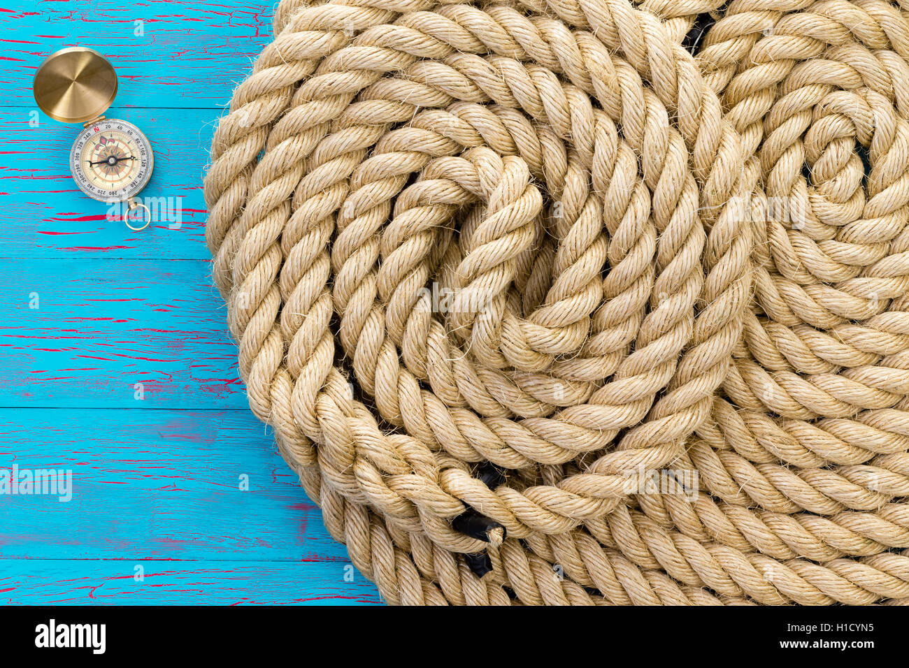 Two neatly coiled ropes and a magnetic compass over a colorful crackle ...