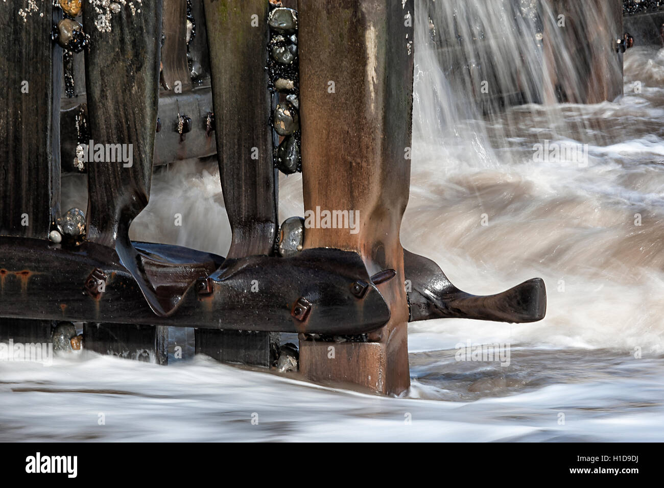 Sea water breaking through groynes on beach in slow motion Stock Photo ...