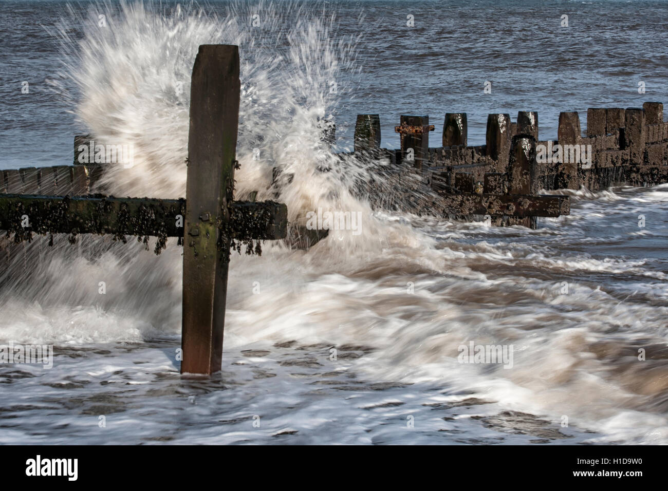 Sea water breaking through groynes on beach in slow motion Stock Photo ...