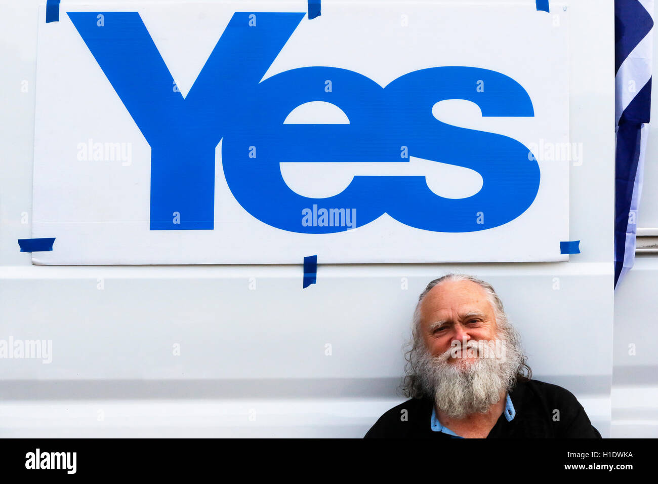 Scottish National Party supporter sitting at a "YES" campaign poster ...