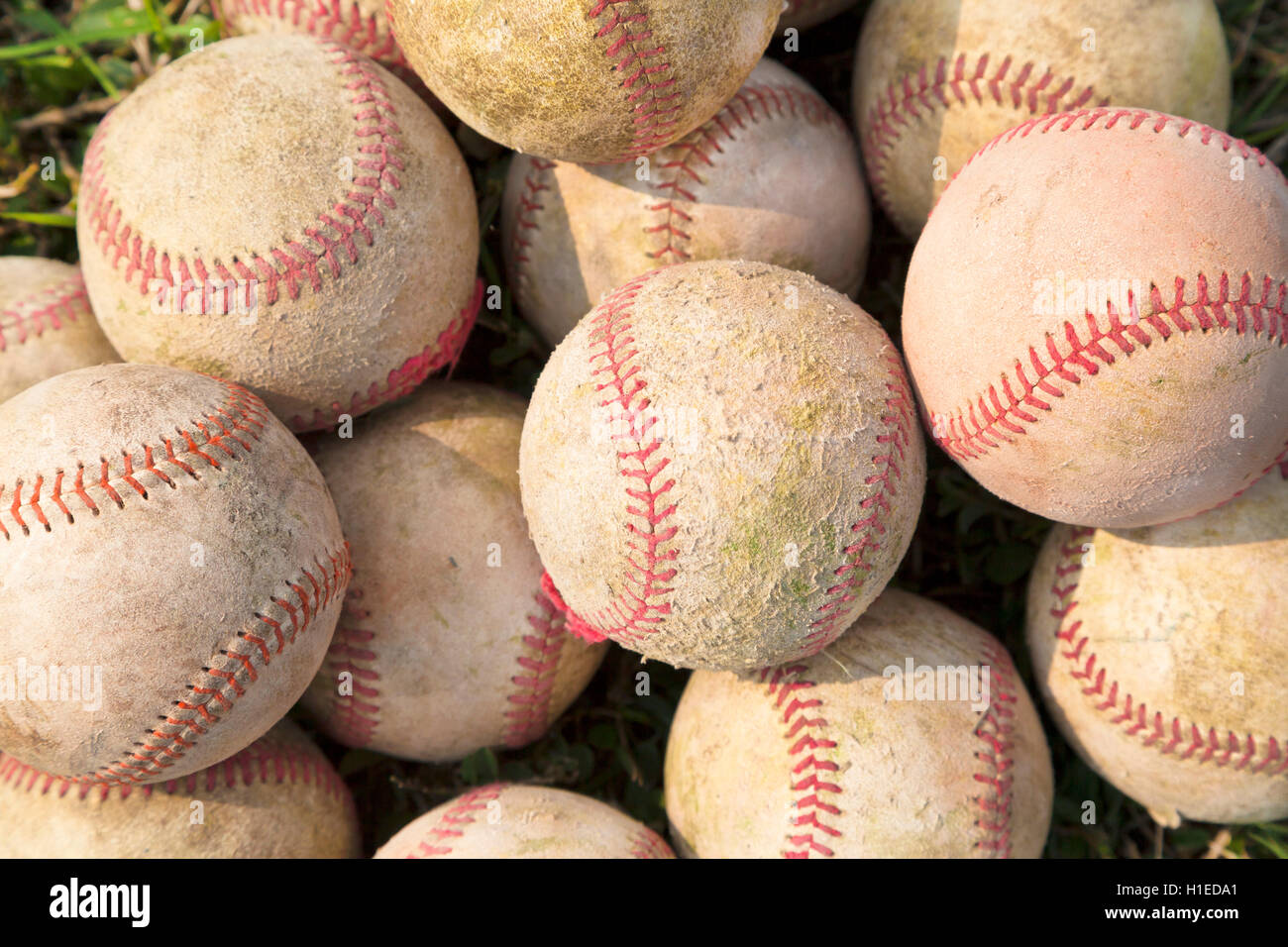Pile up a stack of old baseball in green Stock Photo - Alamy