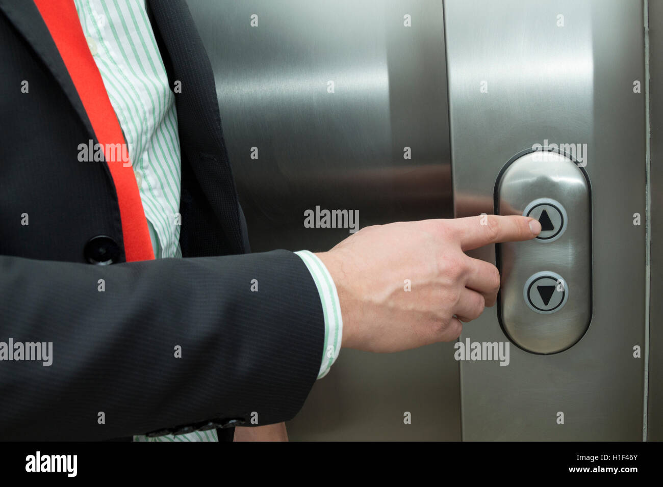 Businessman pressing elevator up button Stock Photo - Alamy