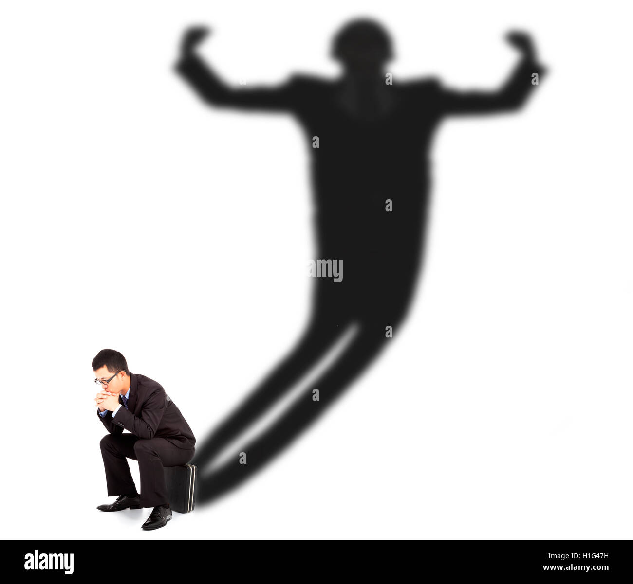 Business man sitting and casting shadow of a strong man Stock Photo - Alamy