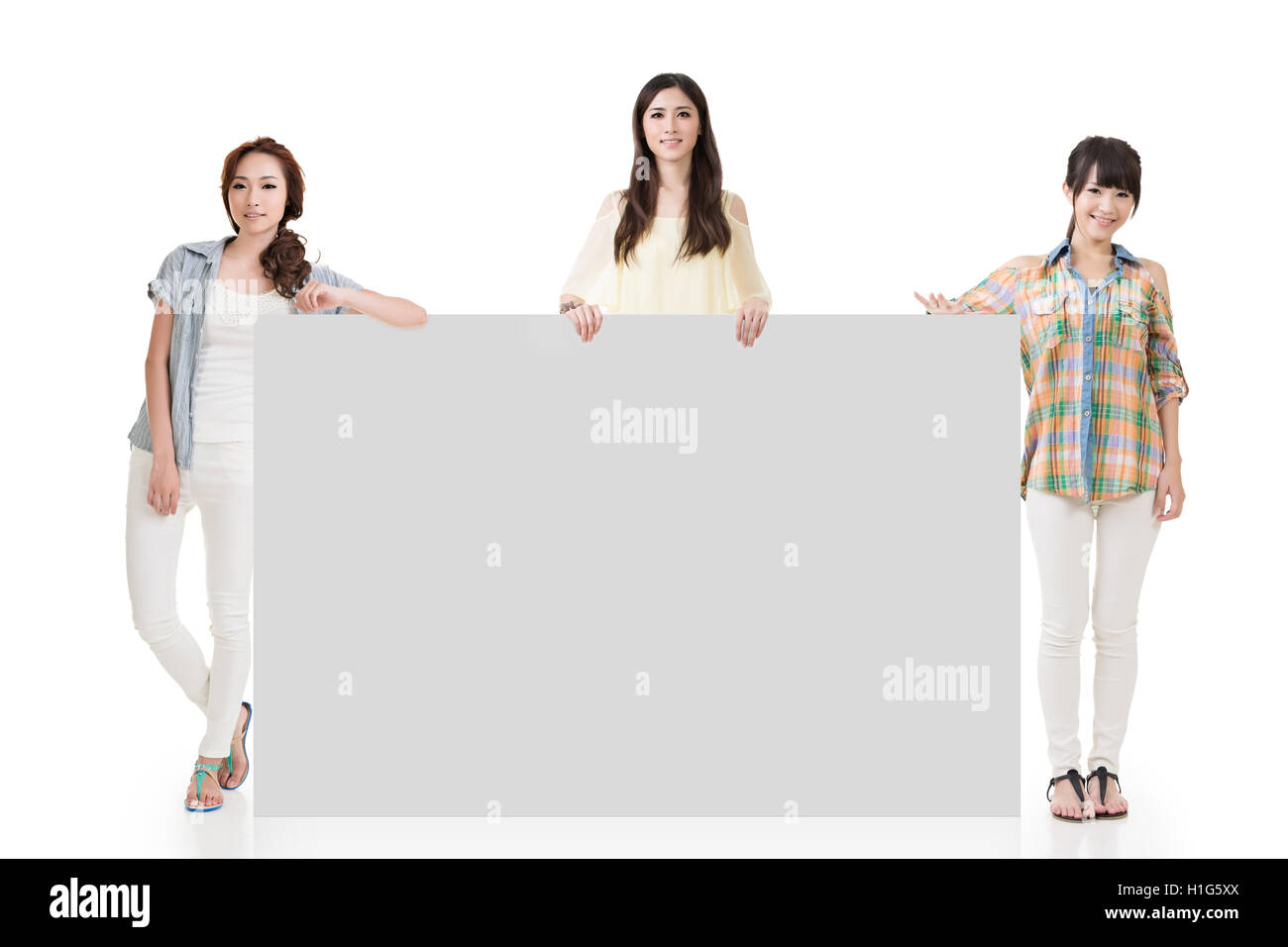 Three pretty women showing an empty board Stock Photo - Alamy