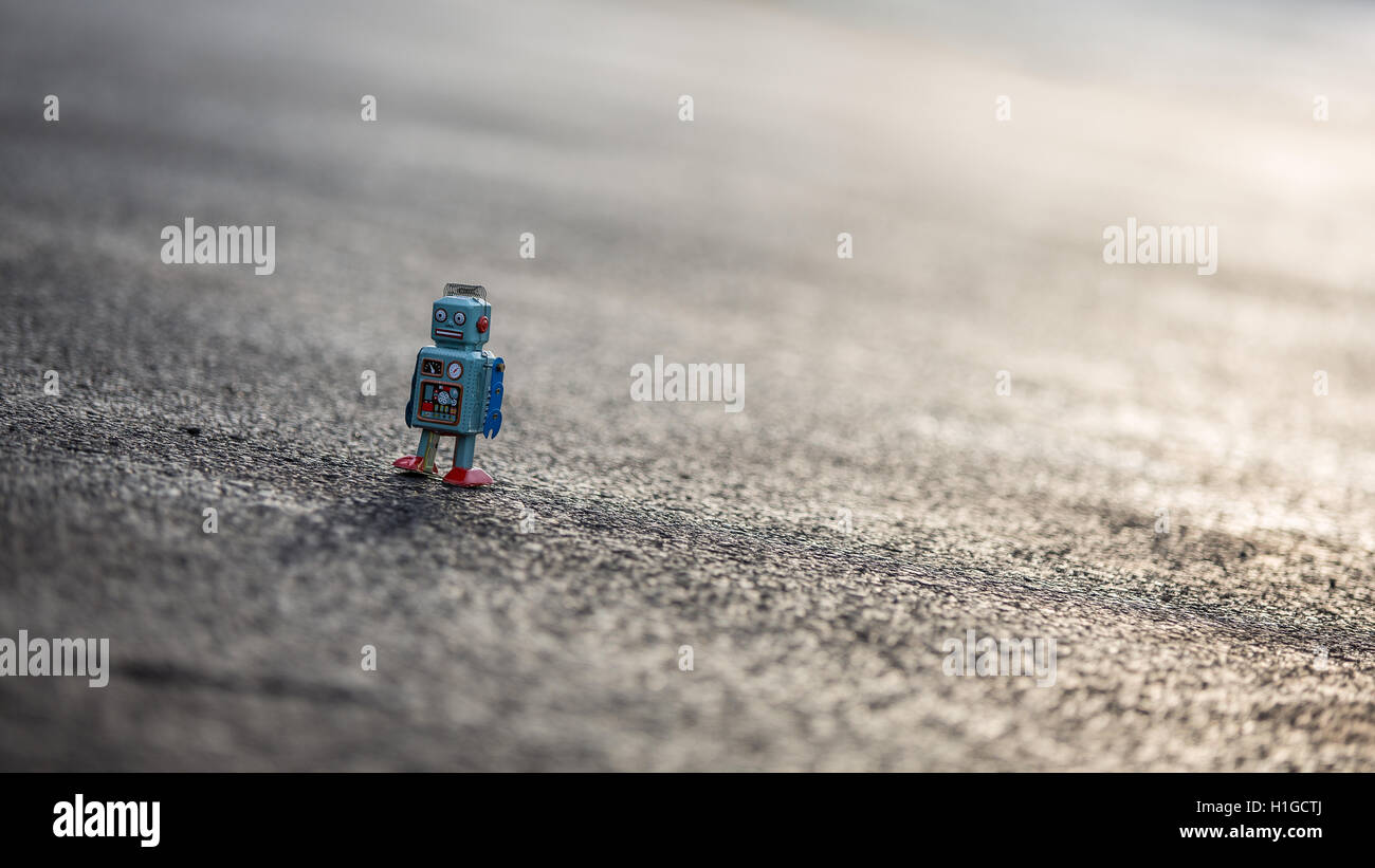 Vintage grey tin robot walking on pavement with blue arms and red feet ...