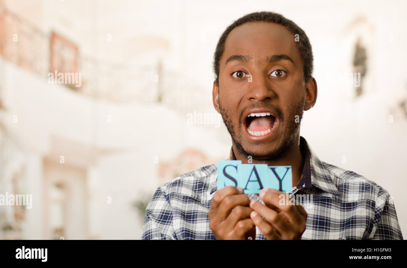 Headshot handsome man holding up small letters spelling the word say ...