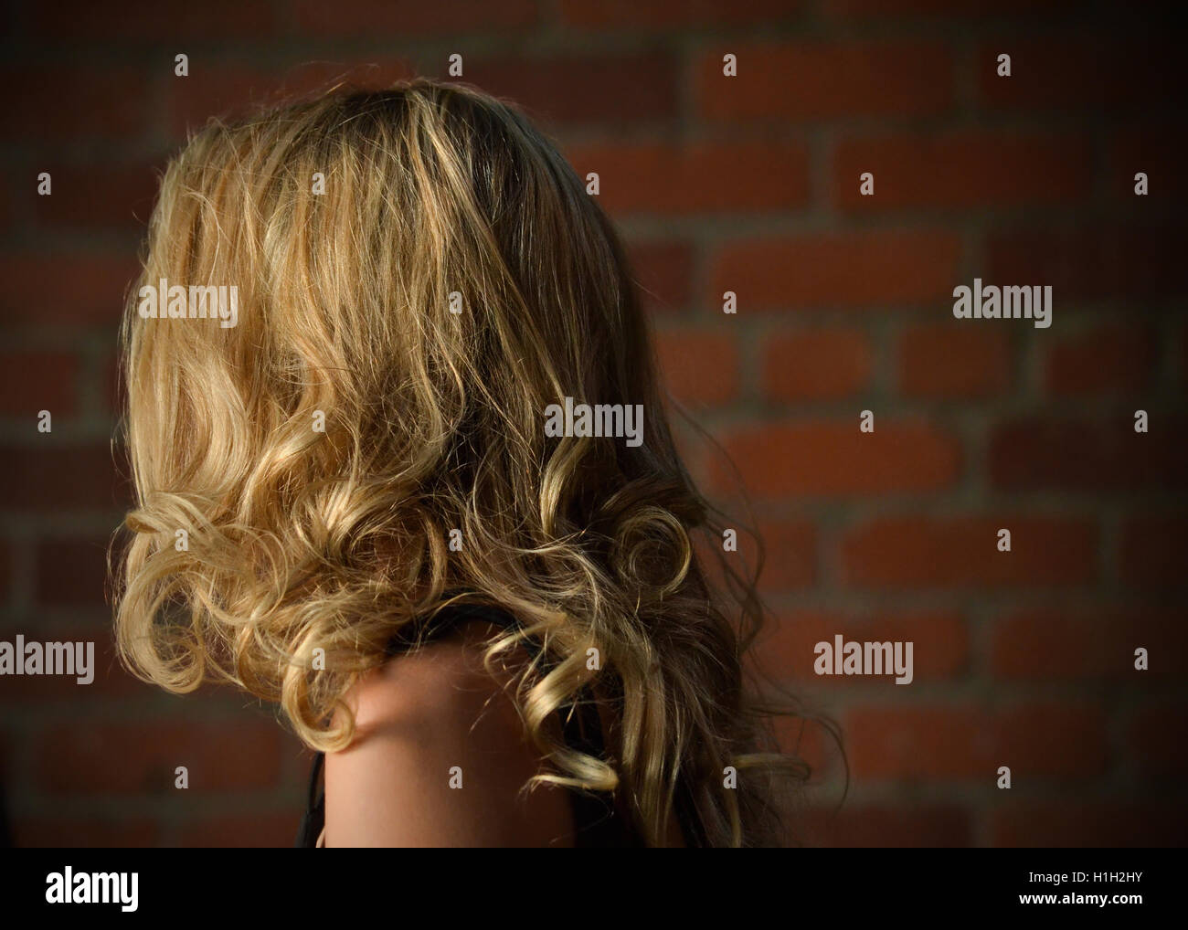 Portrait of the back of the head of blond young female walking alone in ...