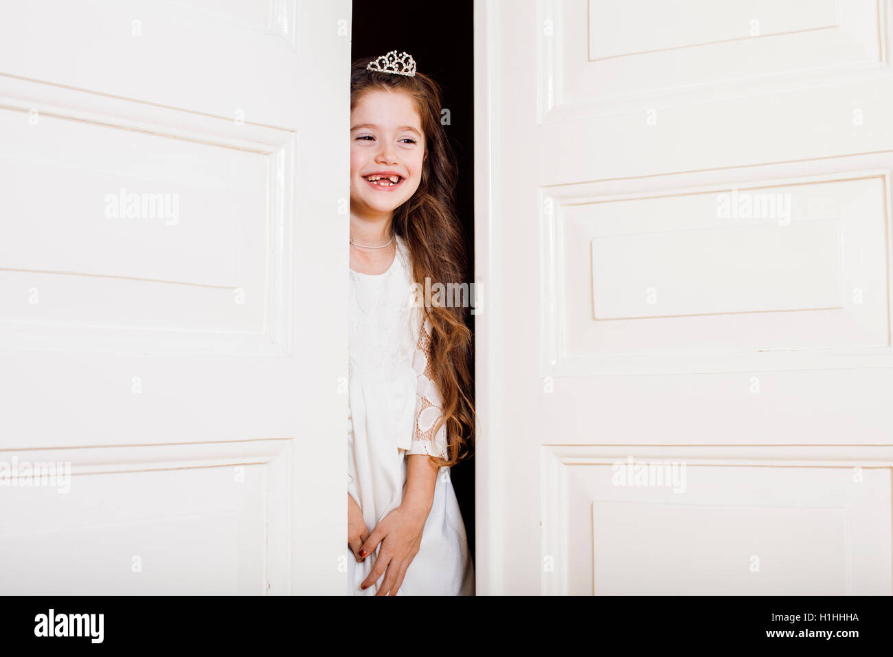 little cute girl at home, opening door well-dressed in white dress ...