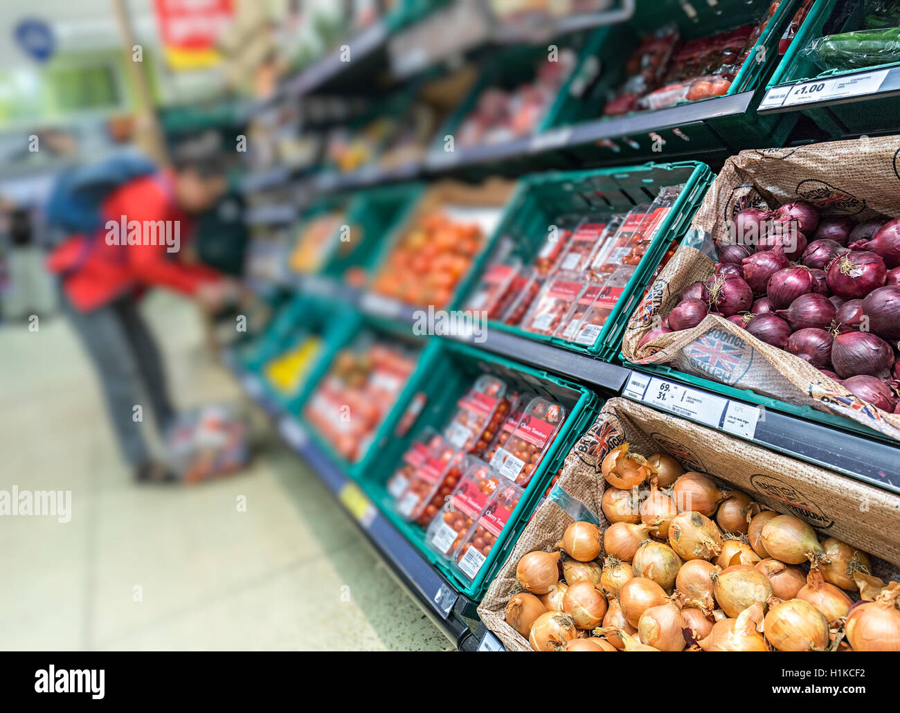 Onions on sale in supermarket produce aisle with woman shopping blurred ...