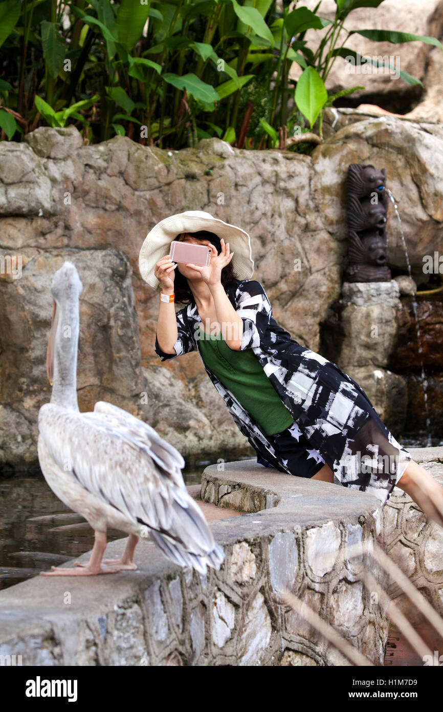 Japanese woman tourist photographing a bird at the KL Bird Park in ...