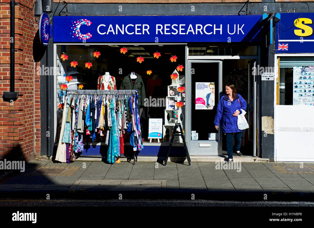 Woman walking out of Cancer Research charity shop, England UK Stock ...