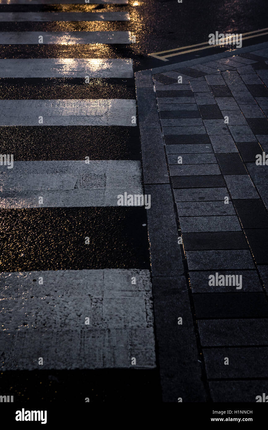 Pedestrian or zebra crossing in the night time with wet rain drenched ...