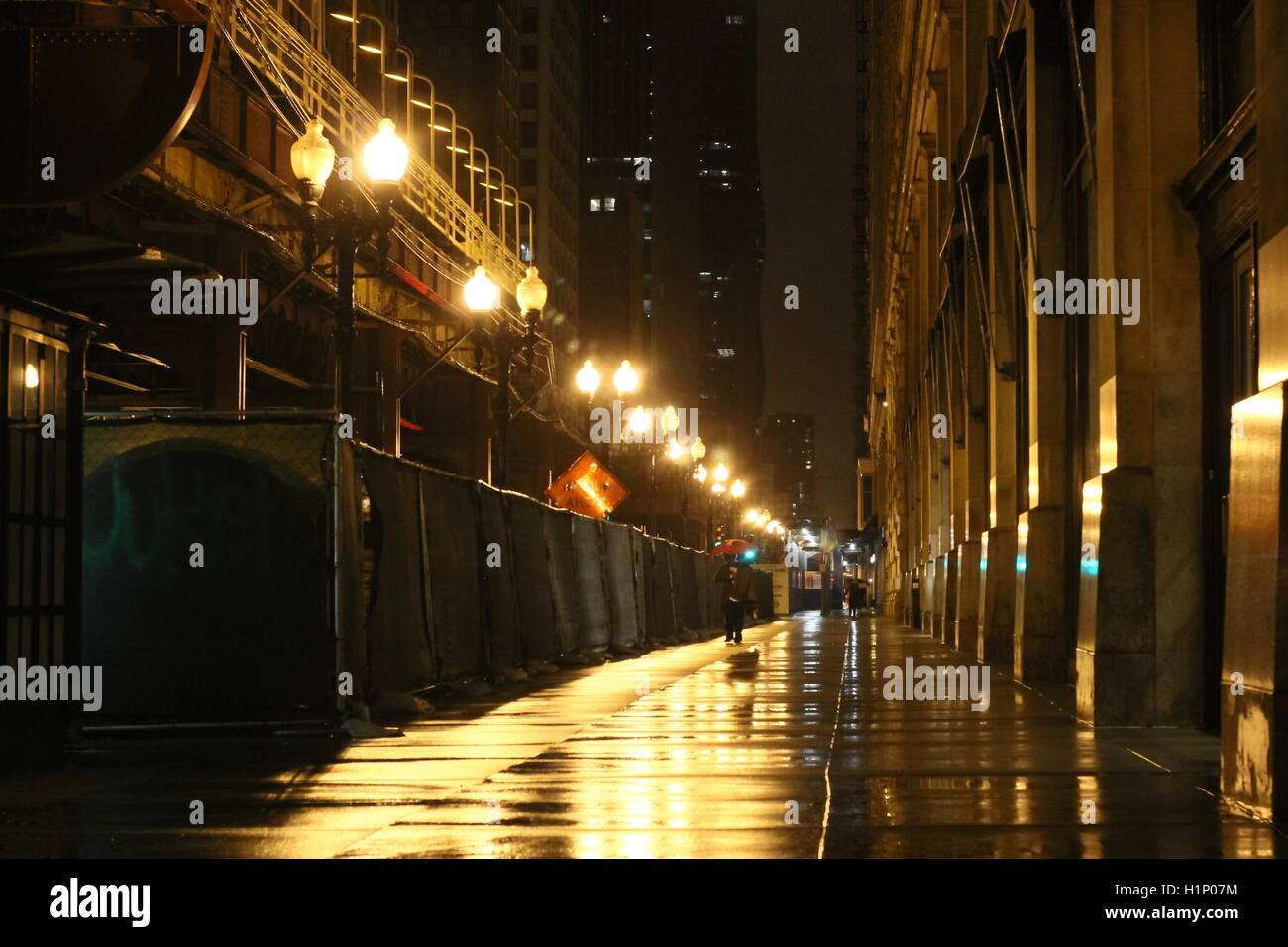 rainy Chicago sidewalk at night with figure in silhouette walking in ...