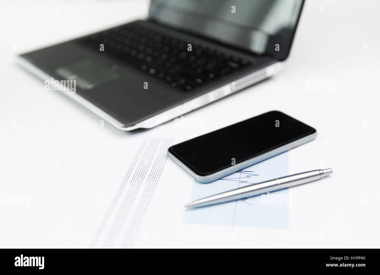 close up of smartphone, laptop and pen on table Stock Photo - Alamy