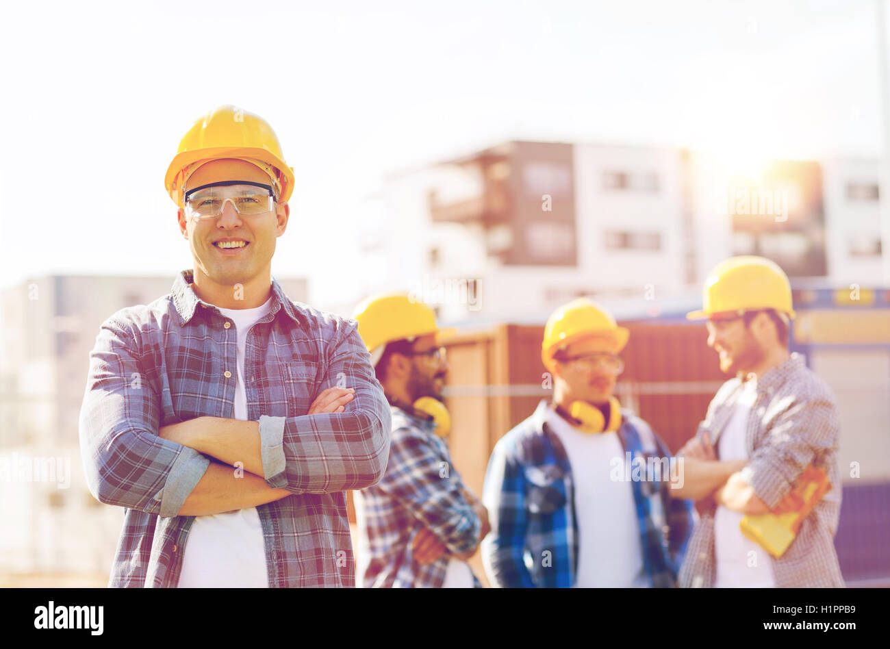 group of smiling builders in hardhats outdoors Stock Photo - Alamy