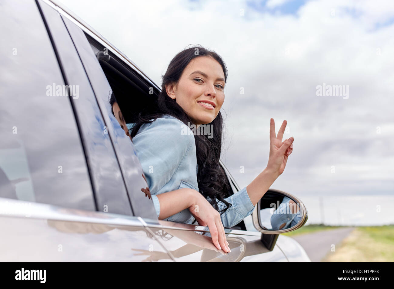 happy woman driving in car showing peace sign Stock Photo - Alamy