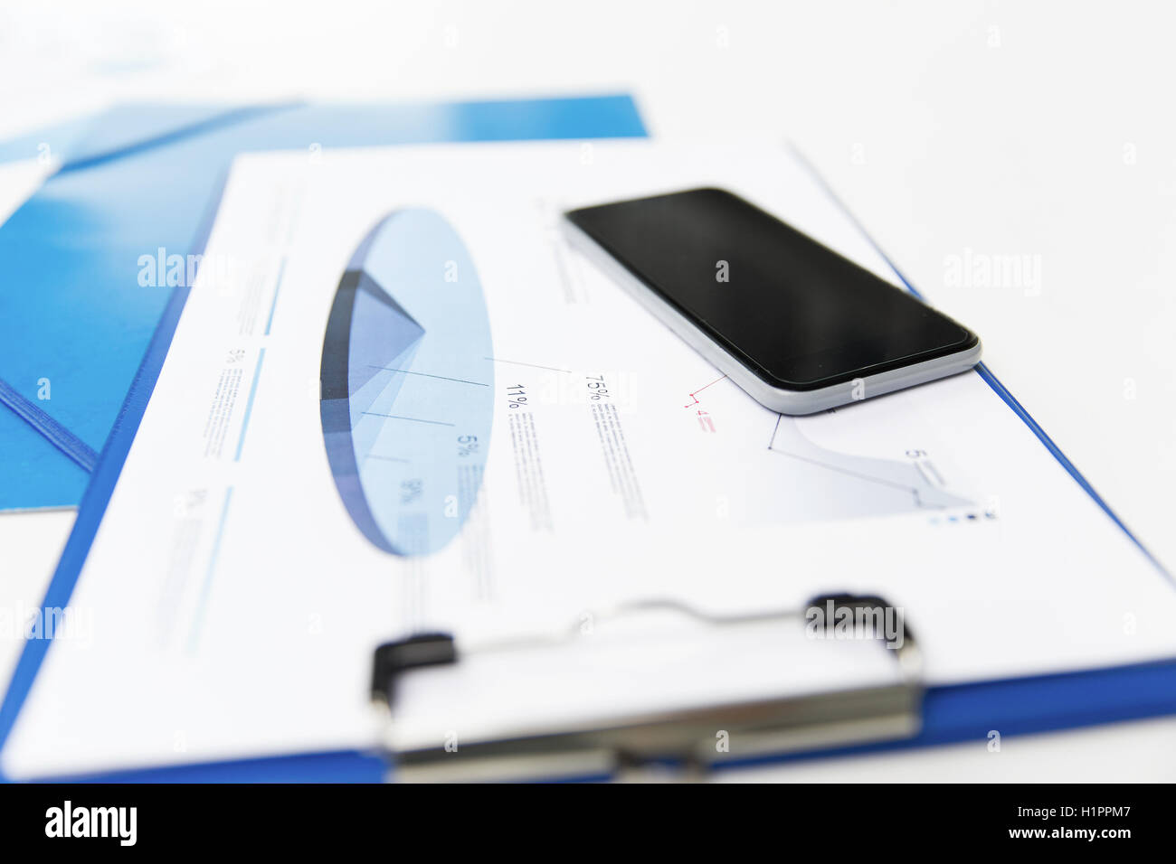 close up of smartphone and clipboard with charts Stock Photo - Alamy