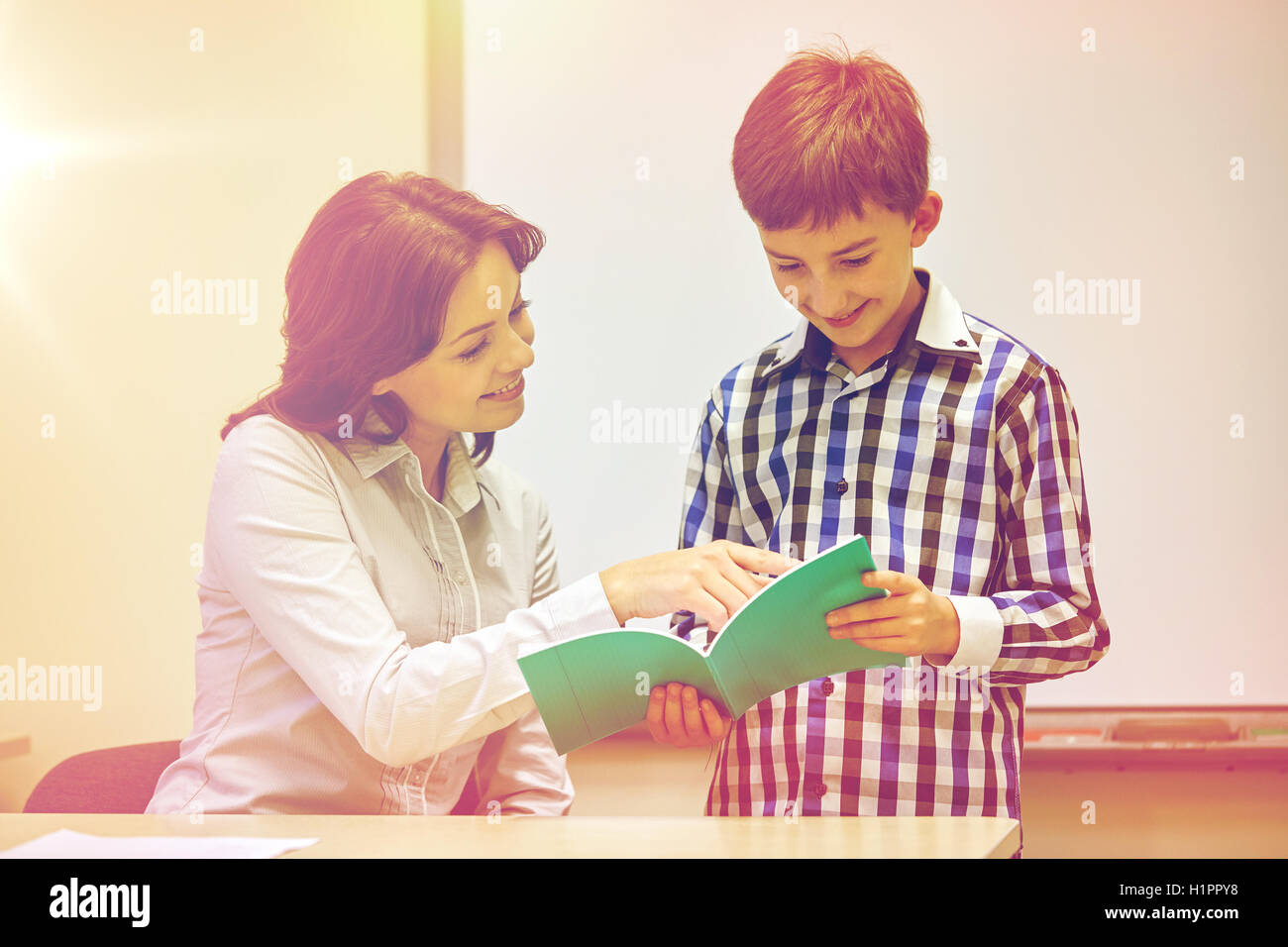 school boy with notebook and teacher in classroom Stock Photo - Alamy