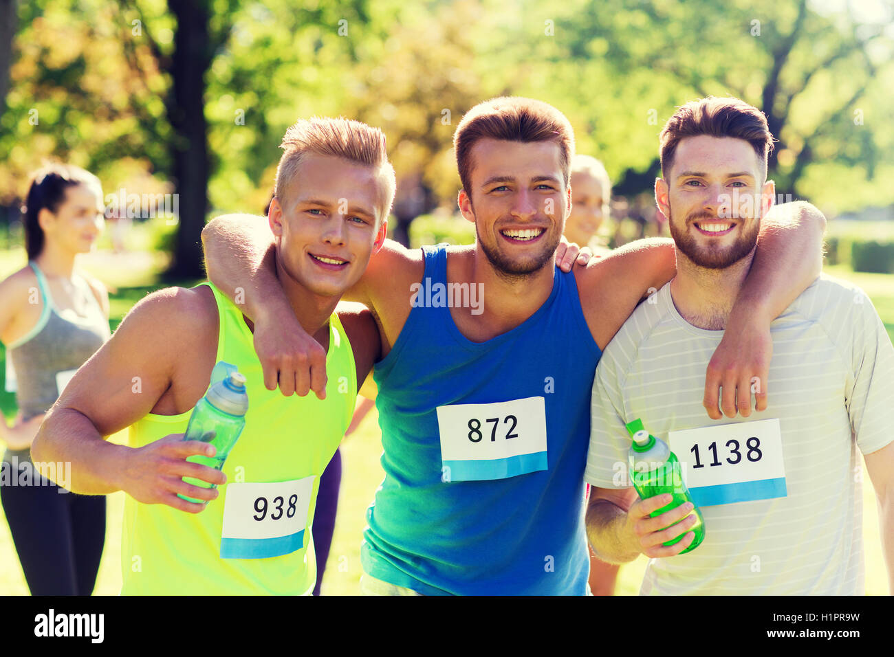 happy friends with racing badge numbers and water Stock Photo - Alamy