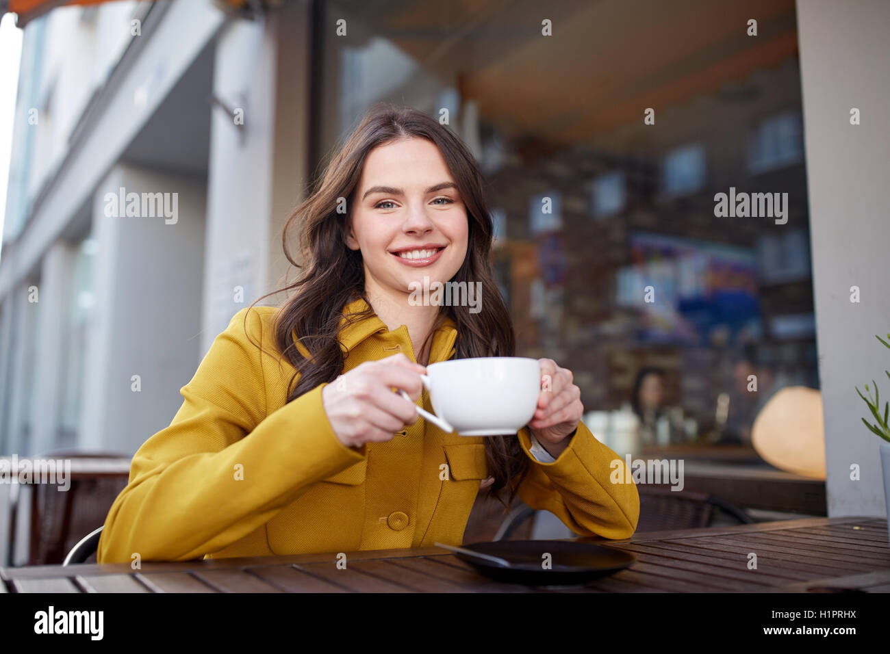 happy woman drinking cocoa at city street cafe Stock Photo - Alamy
