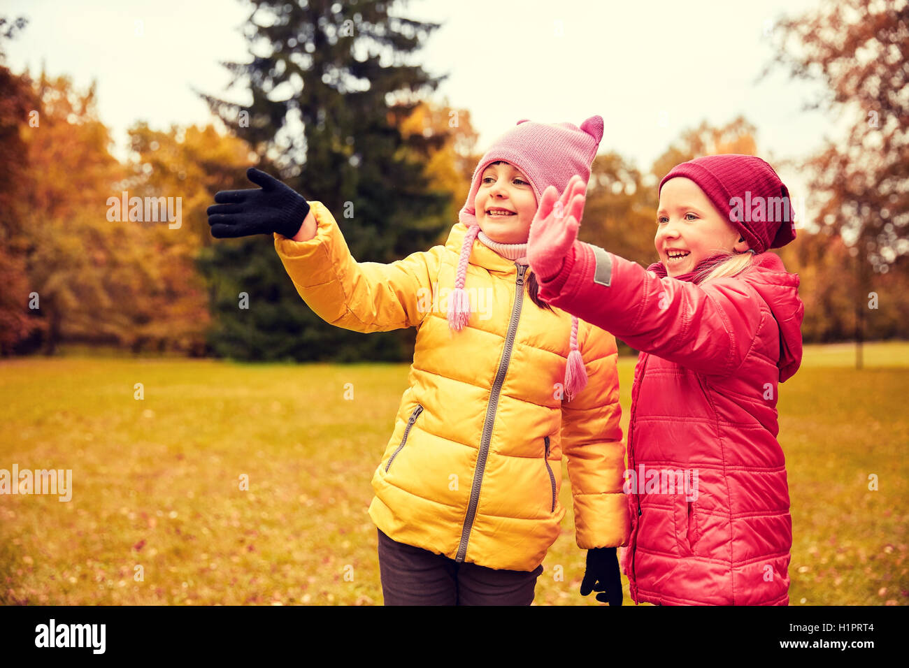 two happy little girls waving hand in autumn park Stock Photo - Alamy