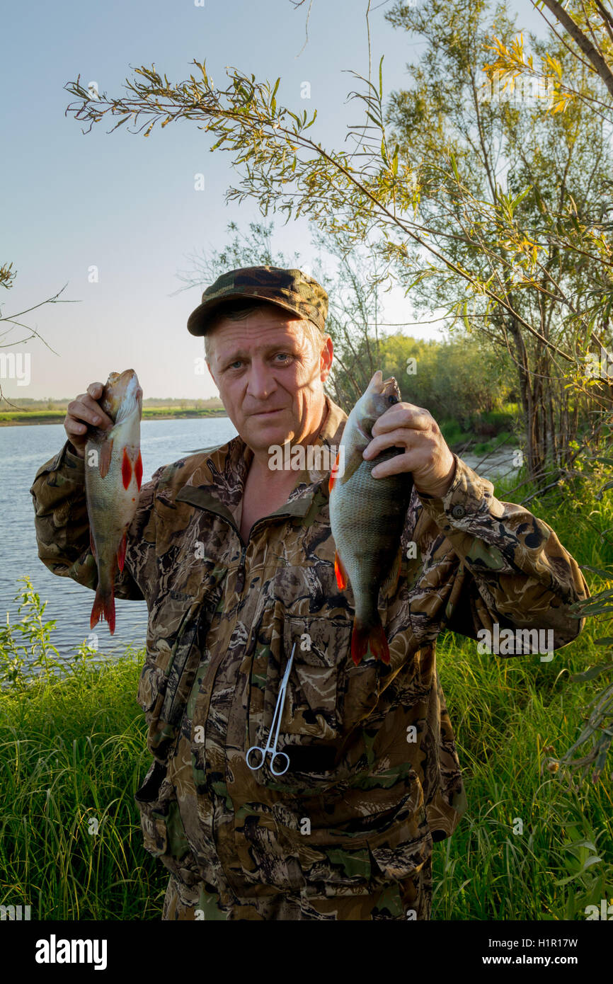 Portrait of a fisherman with a fish on the lake Stock Photo - Alamy