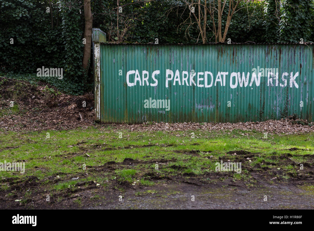 Hand painted sign in a muddy car park, indicating vehciles are left at ...