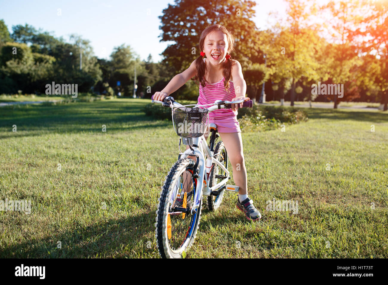 happy child girl riding bicycle in summer sunset in the park. Active kids Stock Photo - Alamy