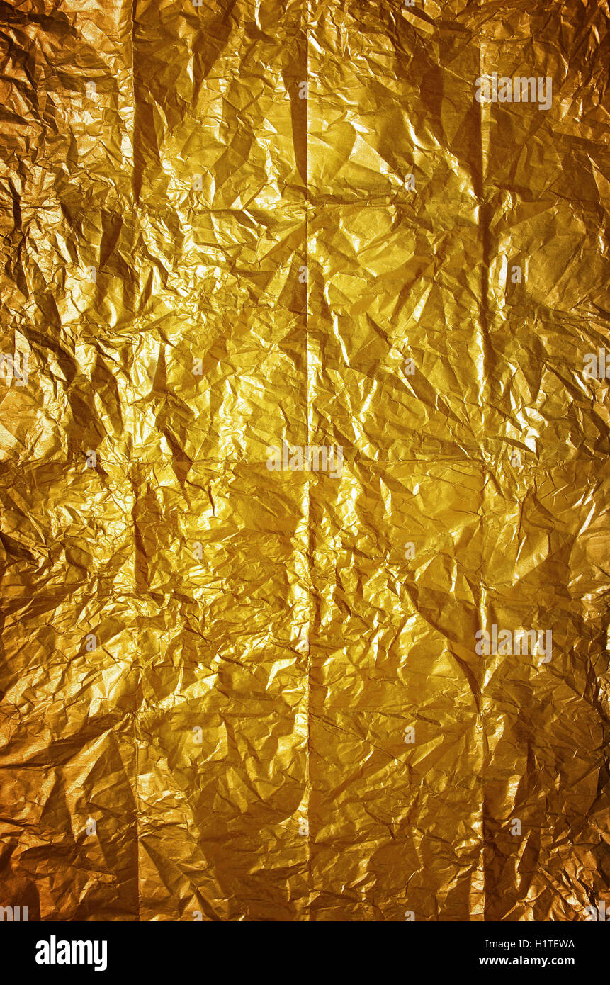 Shining background of old wrinkled and folded yellow wrapping paper ...