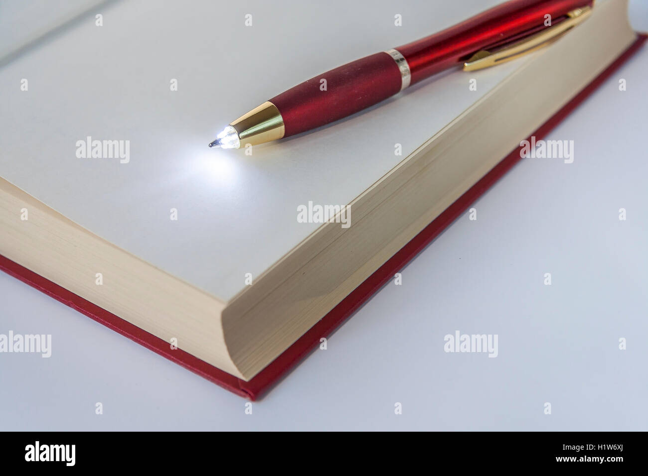 LED Light Ballpoint Pen Lying On Open Book Stock Photo - Alamy