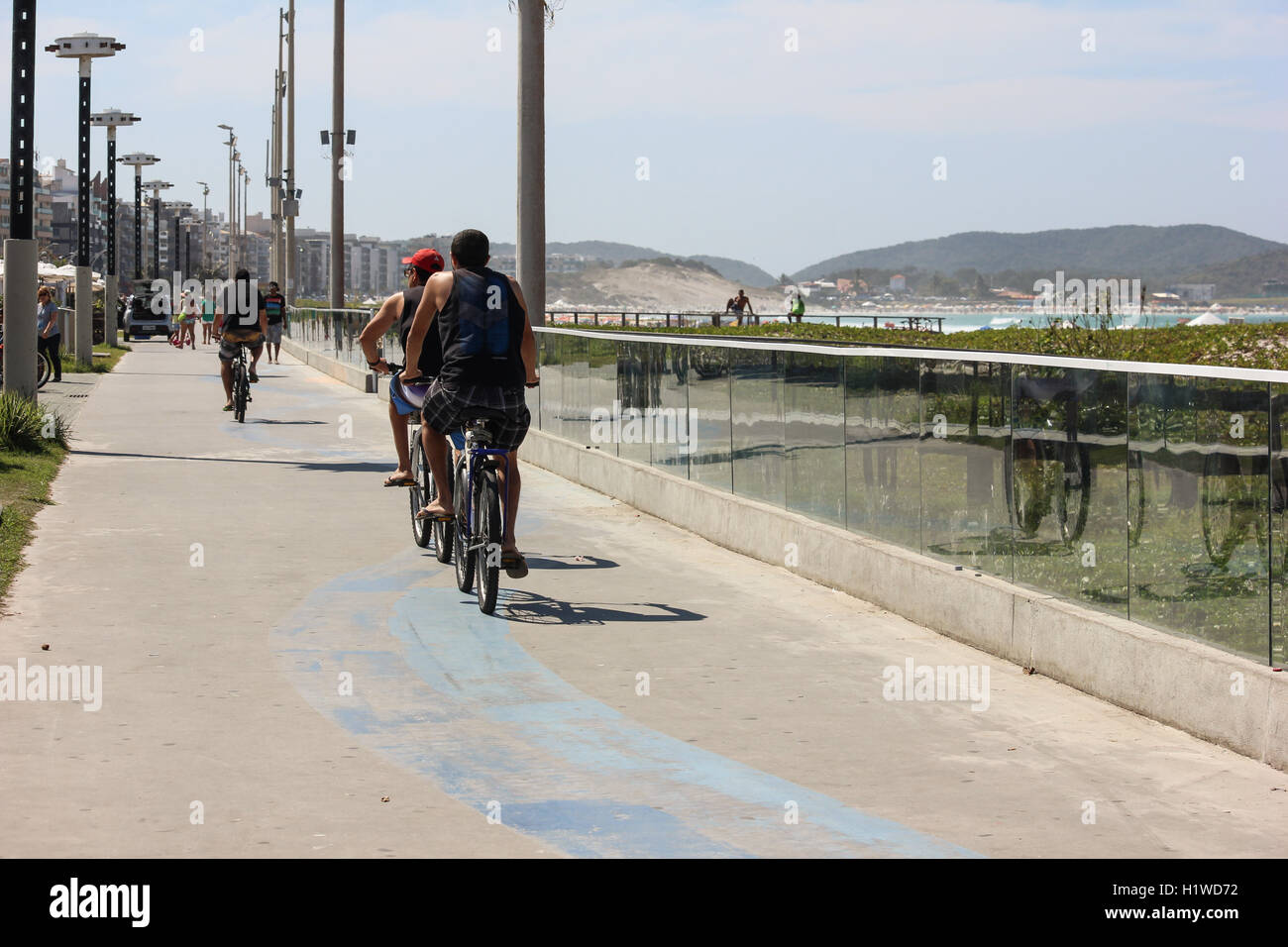 Men ride their bikes on the bike path on the edge of Praia do Forte in Cabo Frio, Rio de Janeiro ...