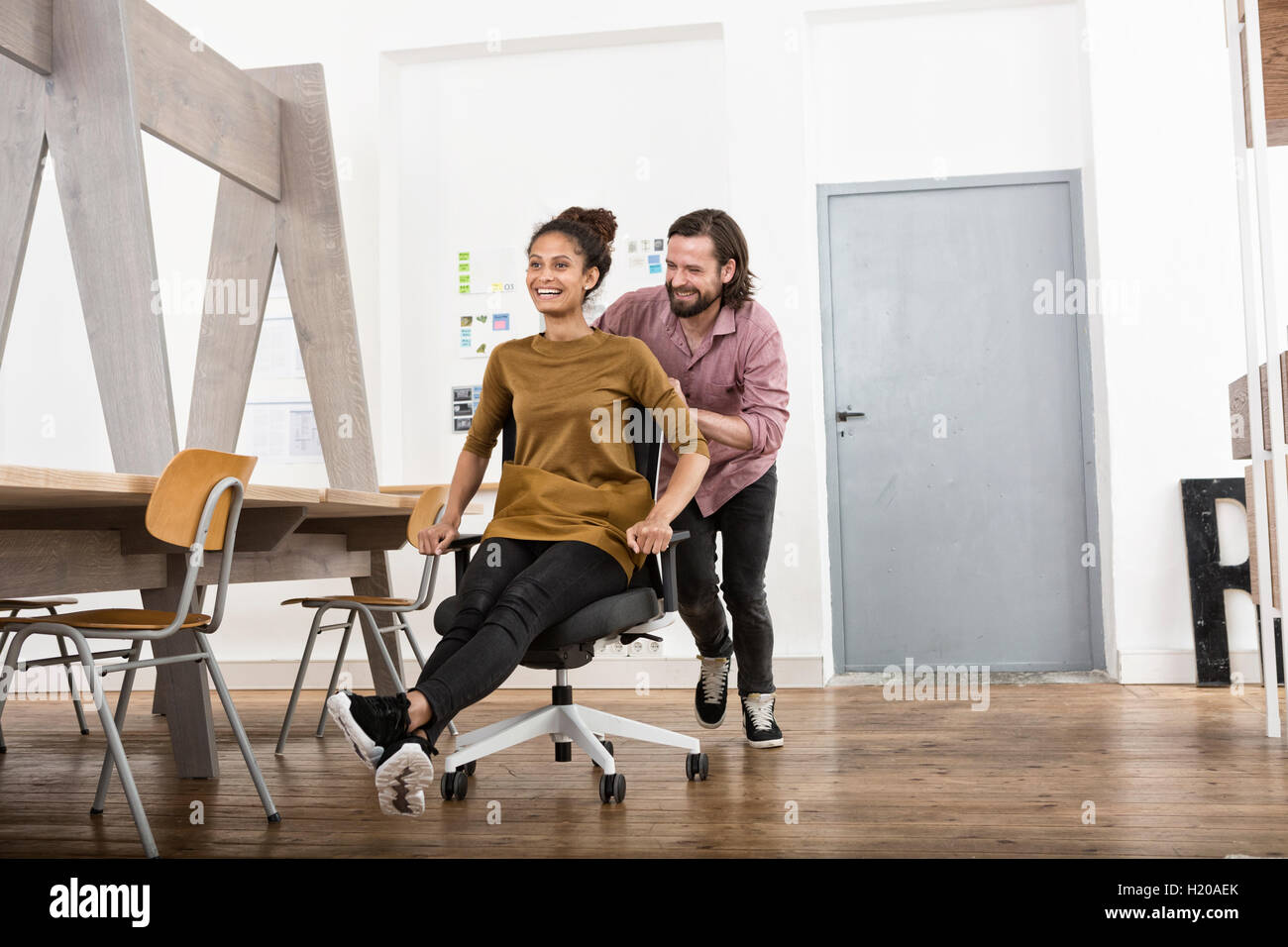 Man pushing happy woman on office chair Stock Photo - Alamy