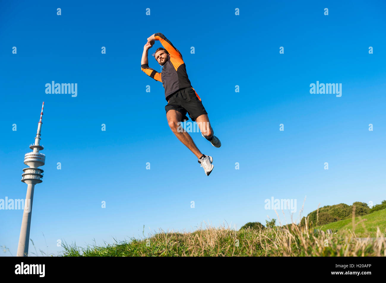 Athlete jumping on meadow under blue sky Stock Photo - Alamy