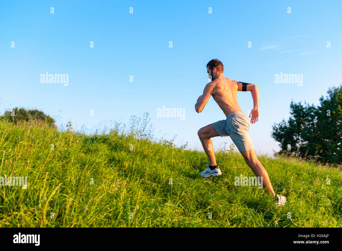 Barechested man running uphill on meadow Stock Photo - Alamy