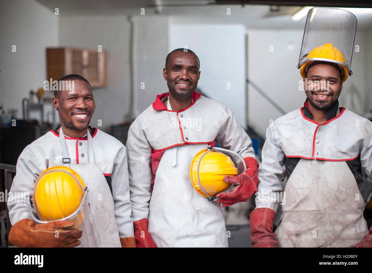 Portrait of three smiling workers with safety helmets Stock Photo - Alamy