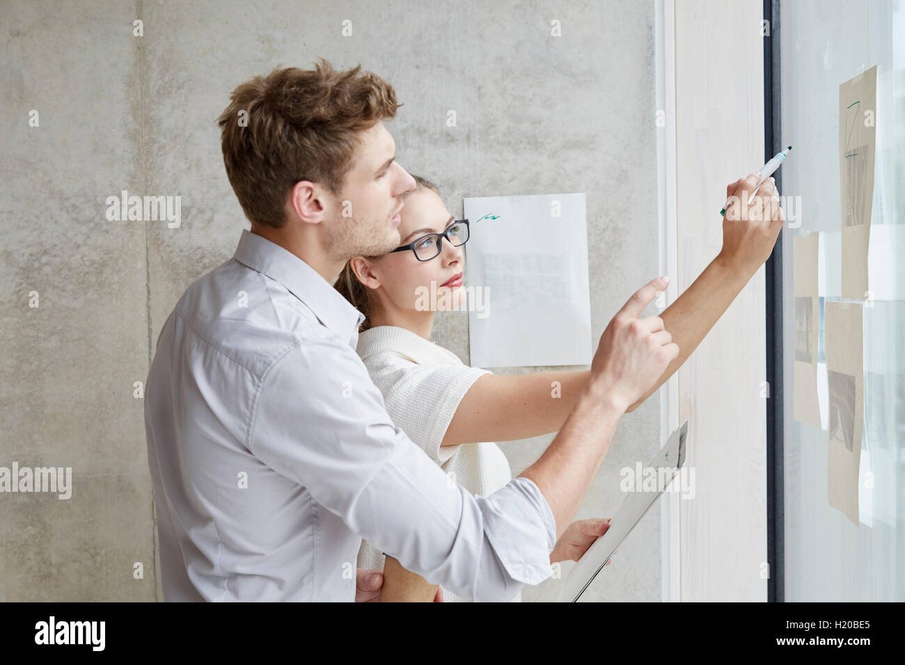 Young man and woman working on draft on glass pane Stock Photo - Alamy
