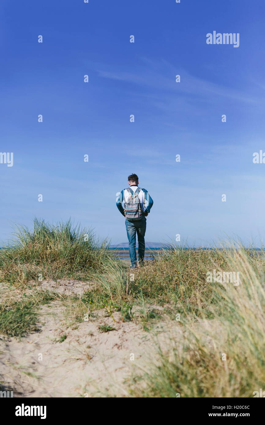 Back view of young man walking on a dune Stock Photo - Alamy