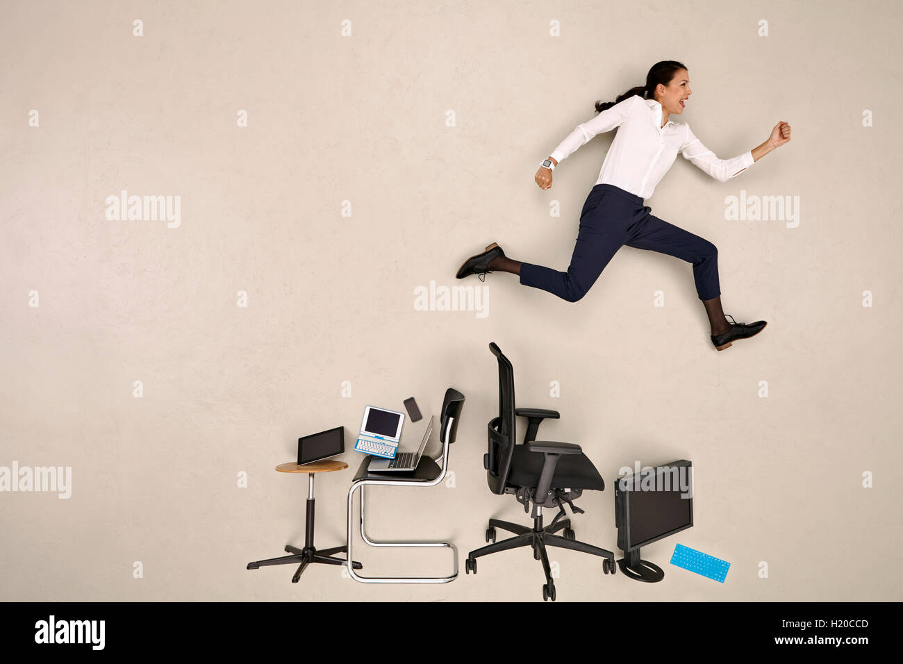 Businesswoman jumping over chairs and devices Stock Photo - Alamy