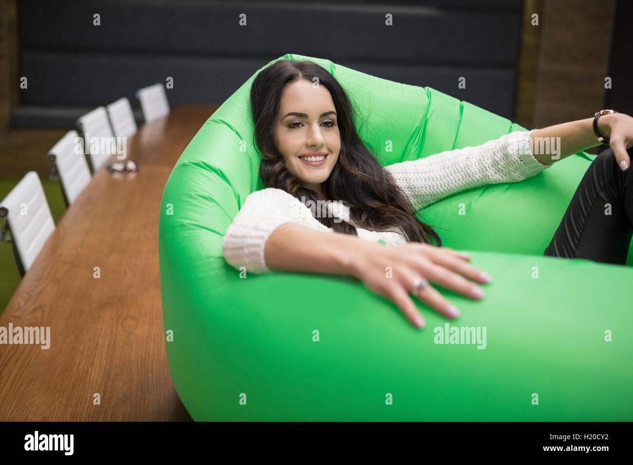 Young woman sitting in inflatable chair on conference table Stock Photo ...