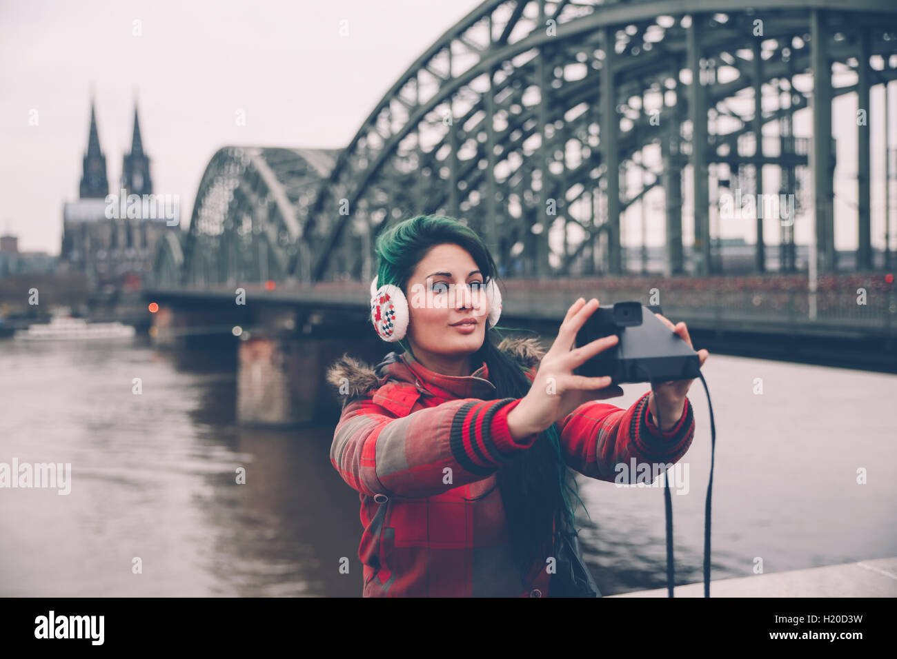 Germany, Cologne, woman taking selfie in front of Hohenzollern Bridge ...