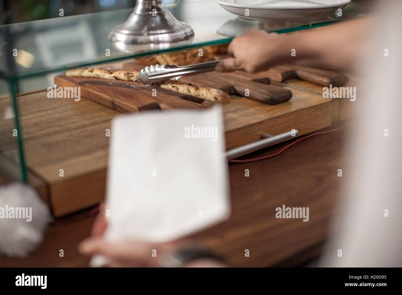 Woman serving roll with pastry tong Stock Photo - Alamy