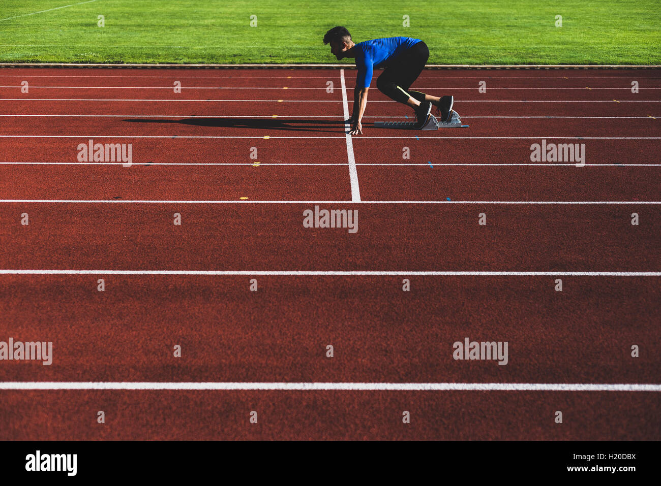 Runner on tartan track in starting position Stock Photo - Alamy