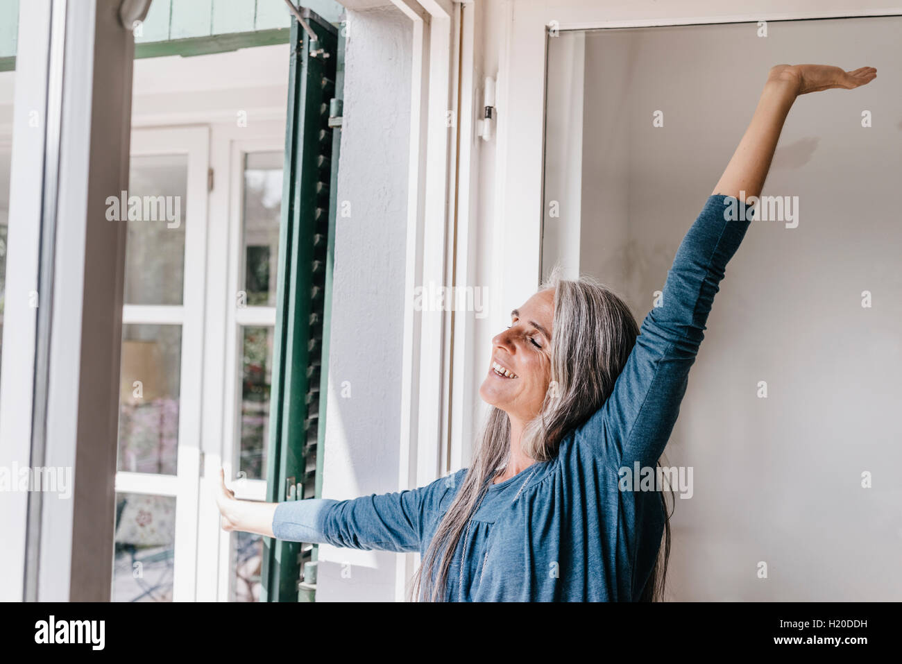 Smiling woman raising her arm Stock Photo - Alamy