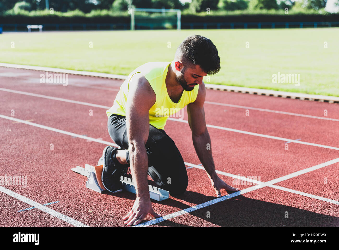 Runner on tartan track in starting position Stock Photo - Alamy