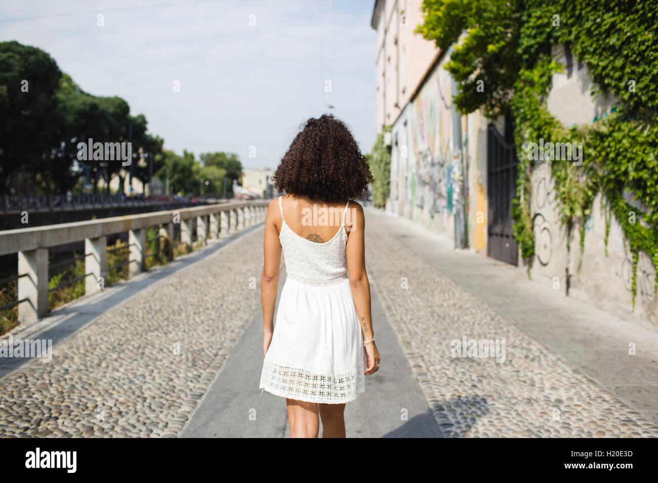 Back view of walking young woman wearing white summer dress Stock Photo ...